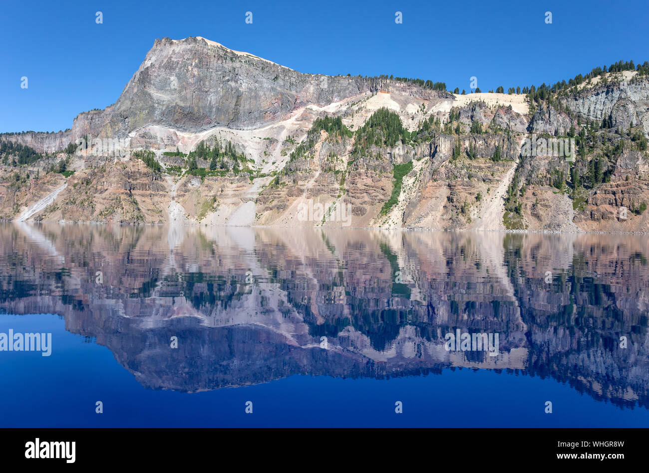A view of Crater Lake rim reflected in its waters. The rim is doted by ...