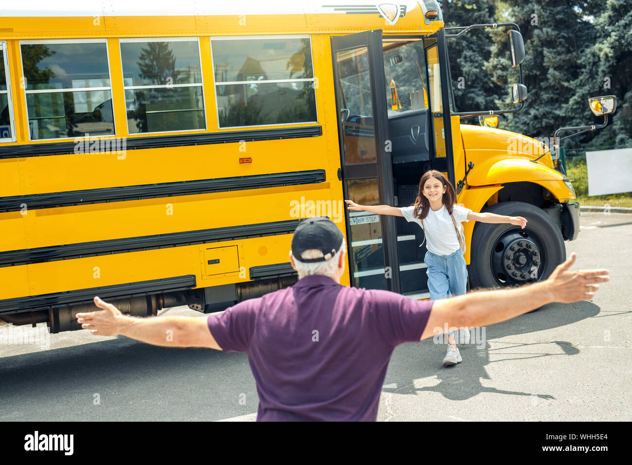 Father meeting little daughter running out of school bus smiling happy ...