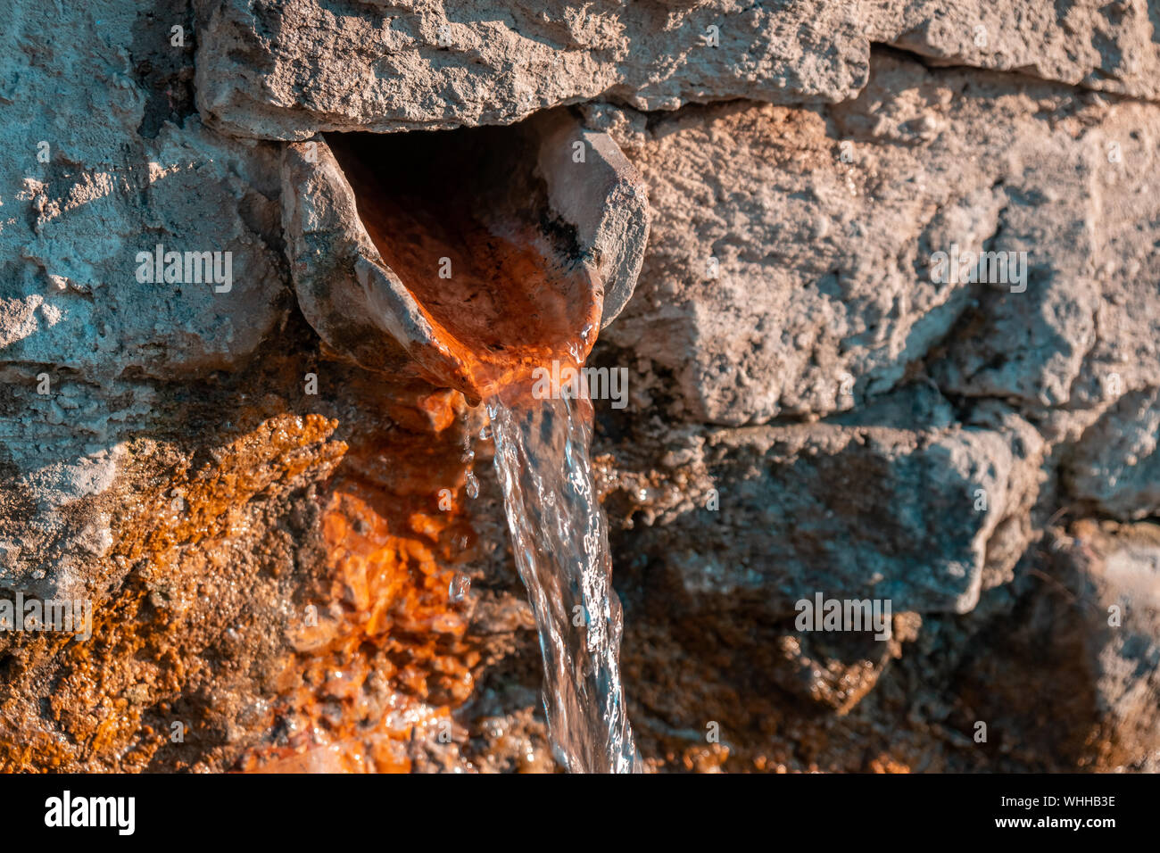 Close up view of a water fountain. Water coming from a hole on the wall ...