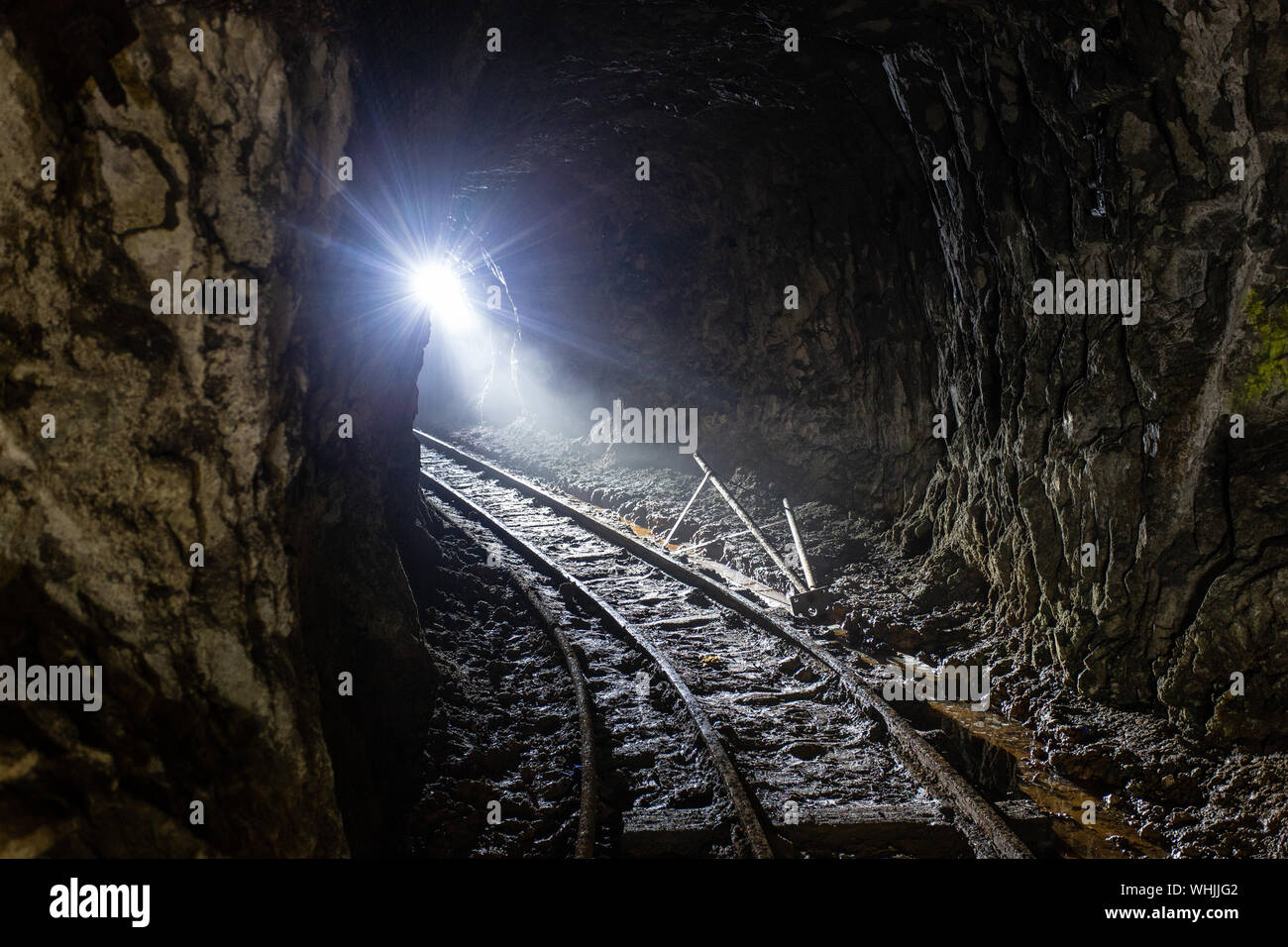 Dark dirty abandoned uranium mine with rusty remnants of railway Stock ...