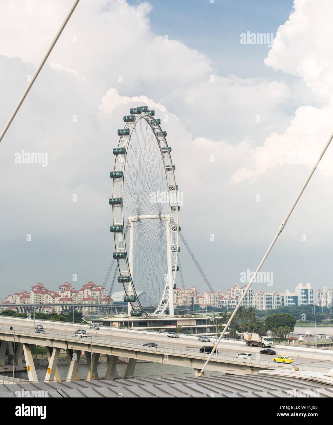 Vertical shot of a Ferris wheel near a bridge and surrounded by ...