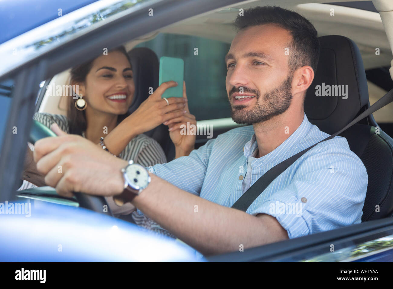 Wife laughing while making photo of husband driving car Stock Photo - Alamy