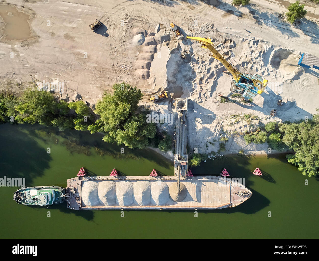 Crane is loading sand and gravel onto barge ship for river transport ...