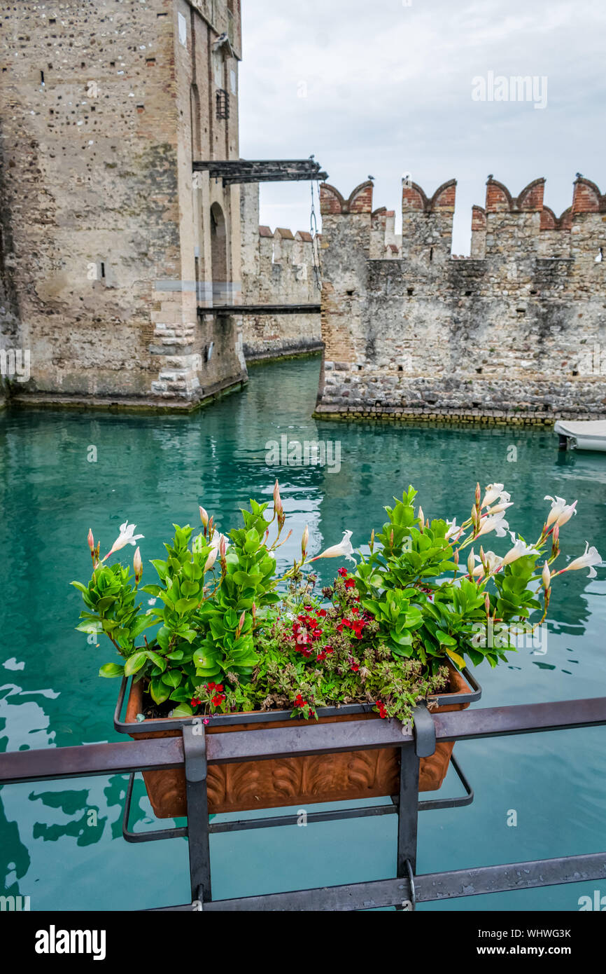 A basket of flowers in front of the walls of a medieval castle on Lake ...