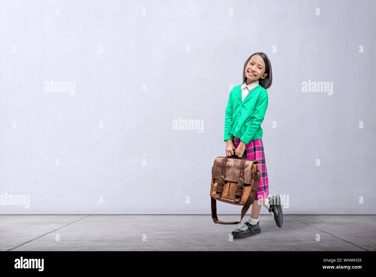 Asian cute girl with a suitcase and happy expression standing with a gray wall background Stock ...