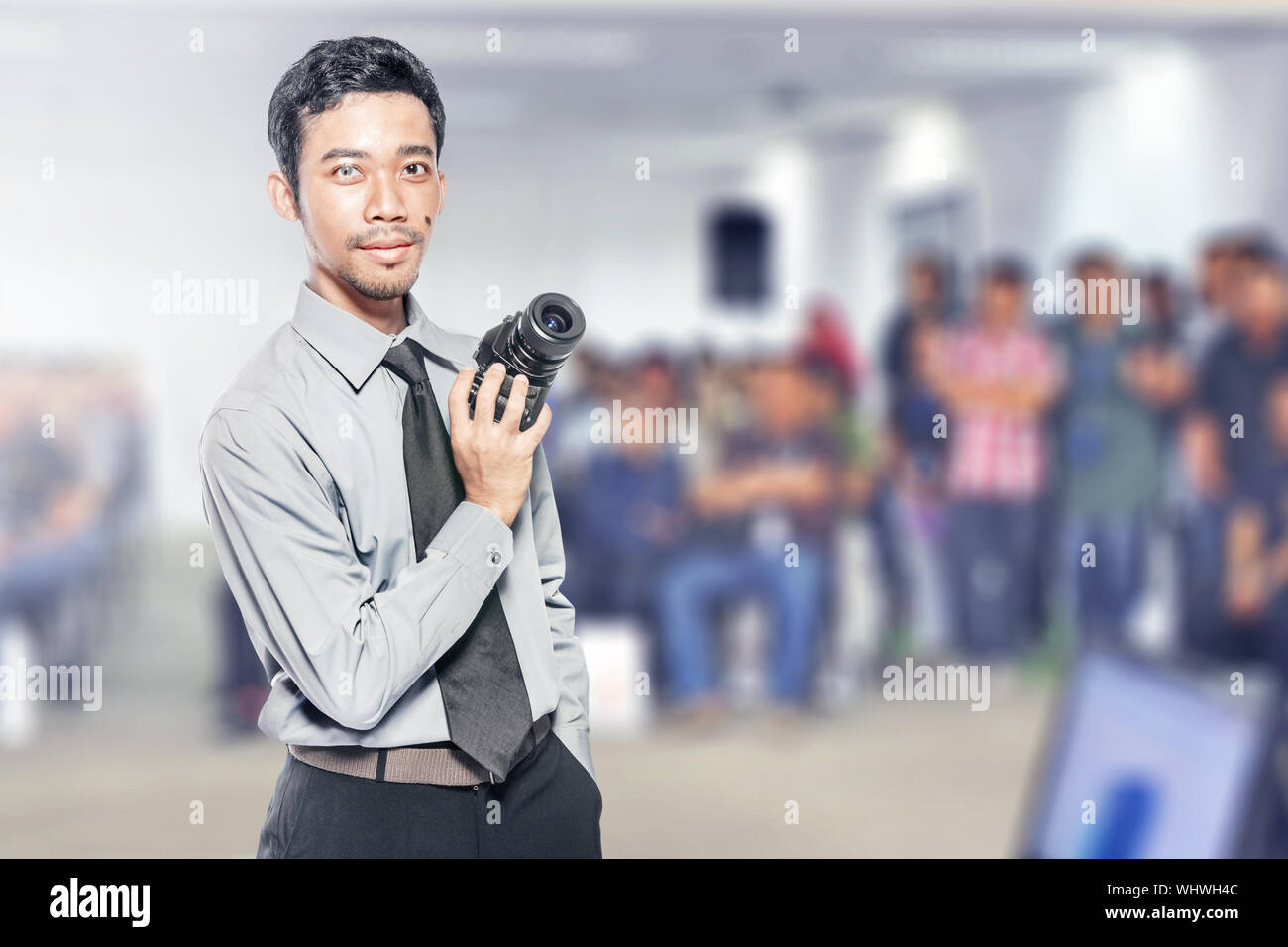 Asian businessman holding the camera on his hand standing on the office ...