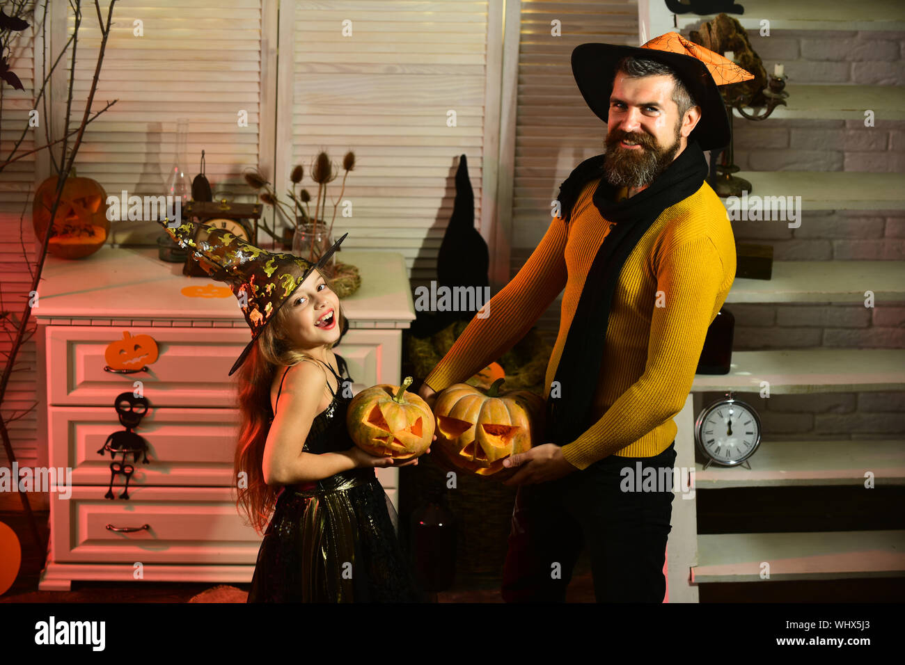 Wizard and little witch in hats hold jack o lanterns. Halloween party ...