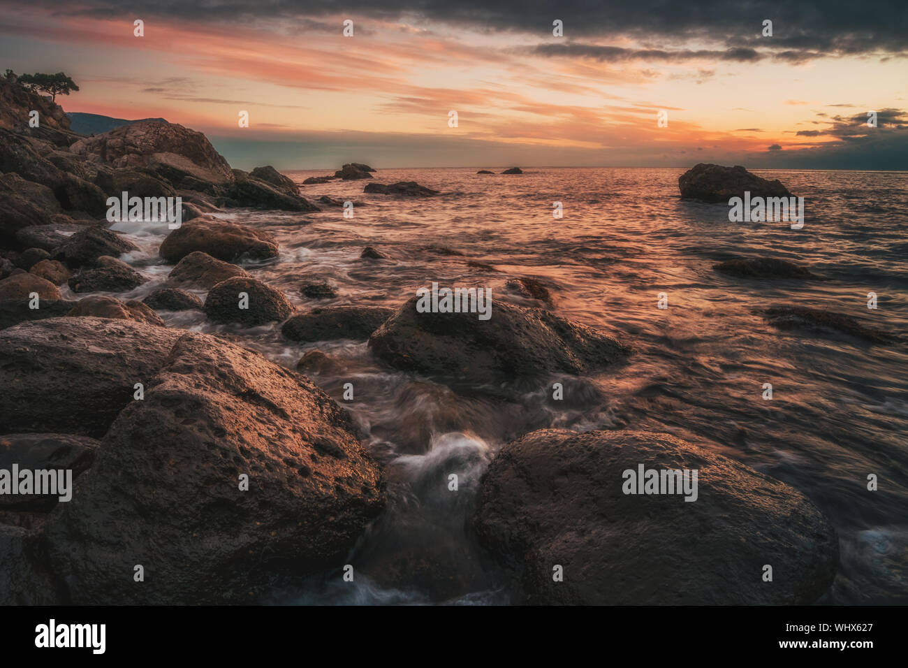 Long exposure of sea and rocks. Wispy Sunset taken with long shutter ...