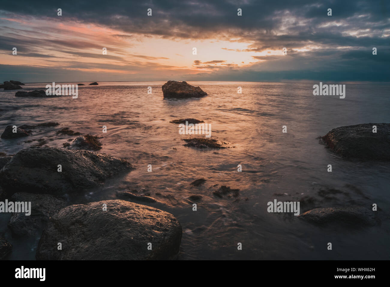 Long exposure of sea and rocks. Wispy Sunset taken with long shutter ...