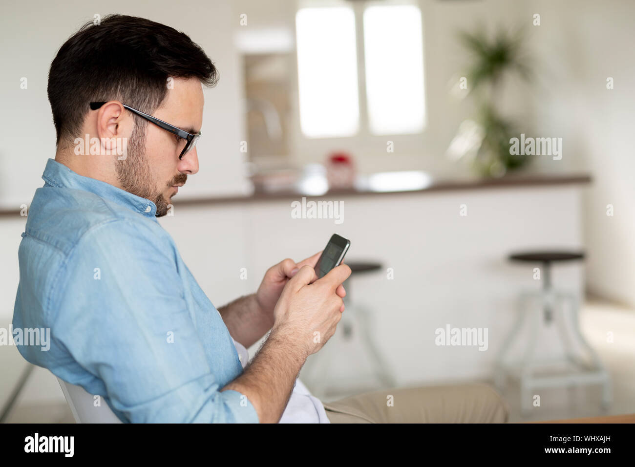 Happy man using mobile phone at home Stock Photo - Alamy