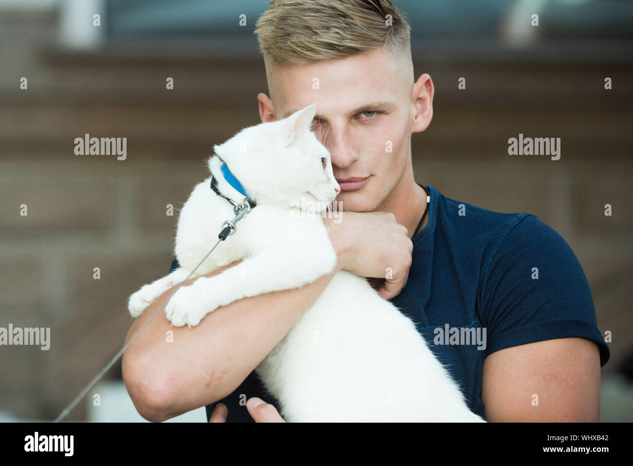 He is more than just a pet. Happy cat owner with muscular look. Cat ...