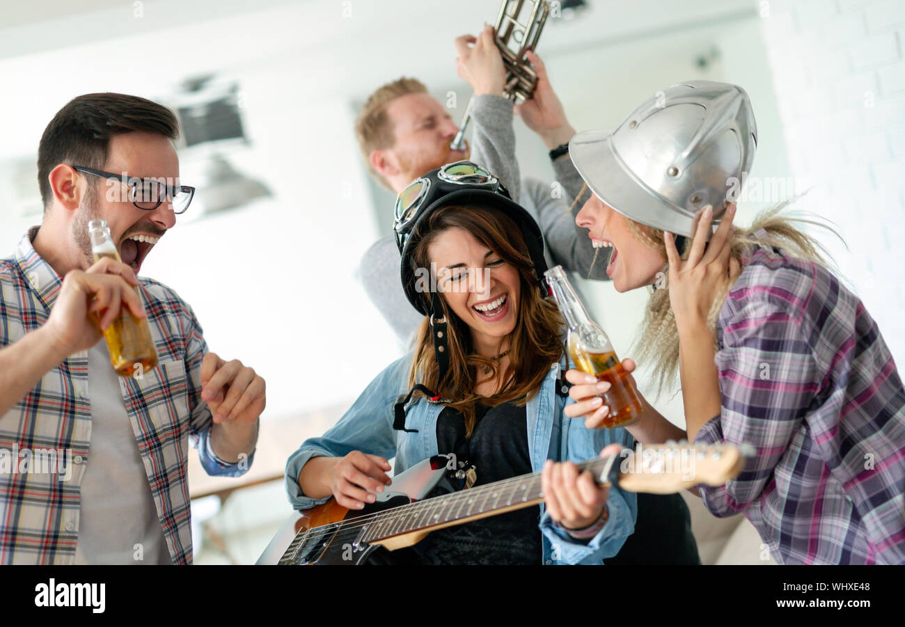 Group of young friends having fun together and playing in music band ...