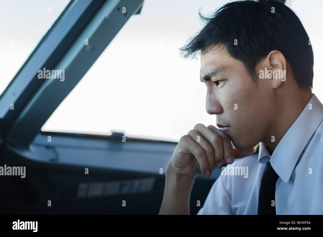 Side portrait of an asian pilot thinking about a problem in the ...