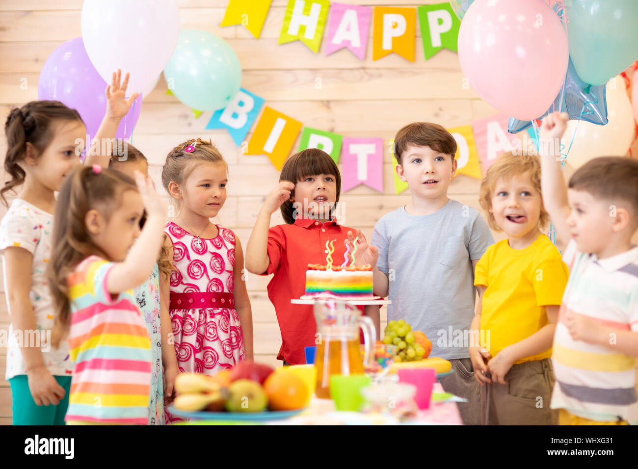 Group of adorable kids gathered around festive table. Birthday children ...
