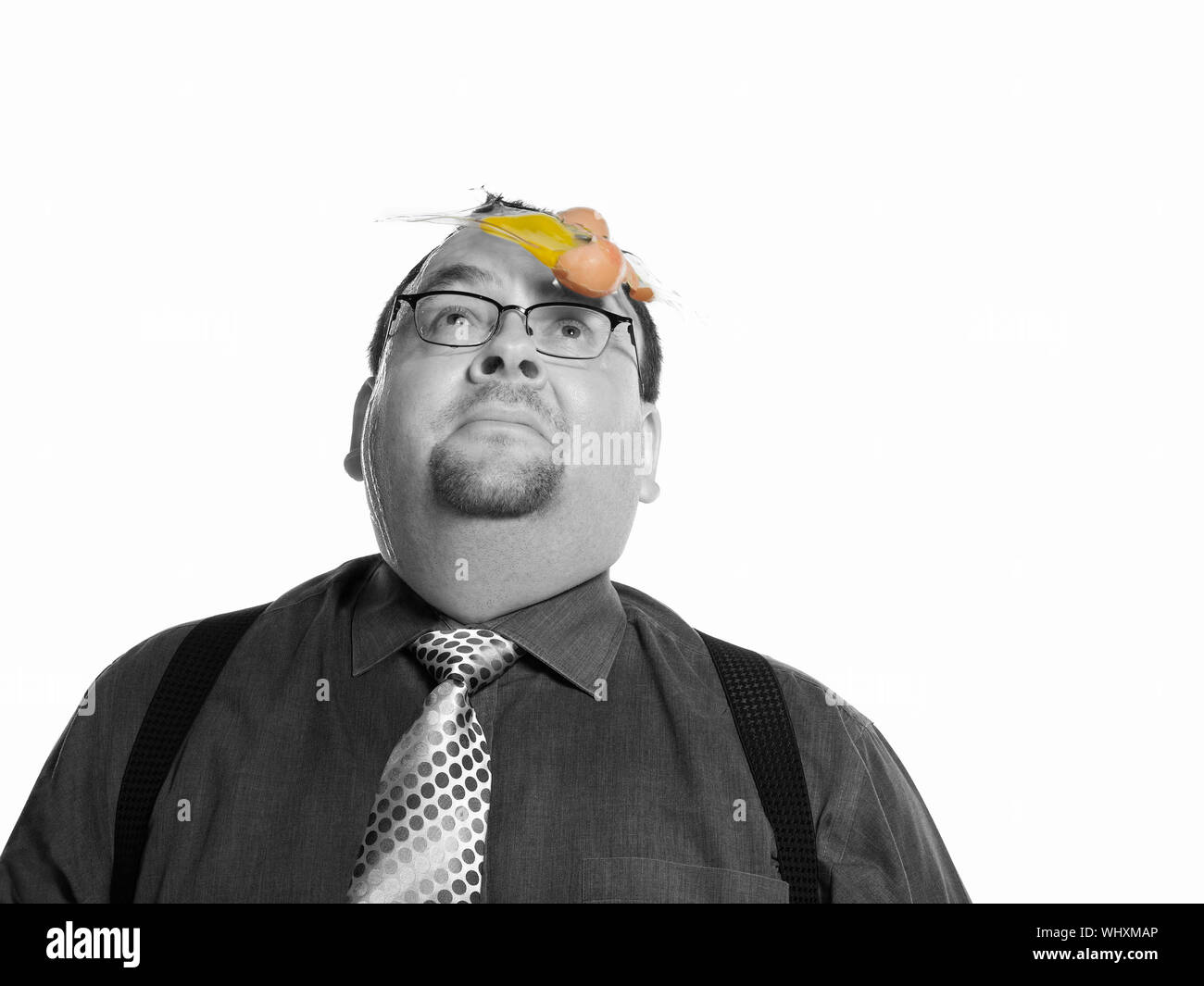 Closeup of a businessman with egg hit on his face against white ...