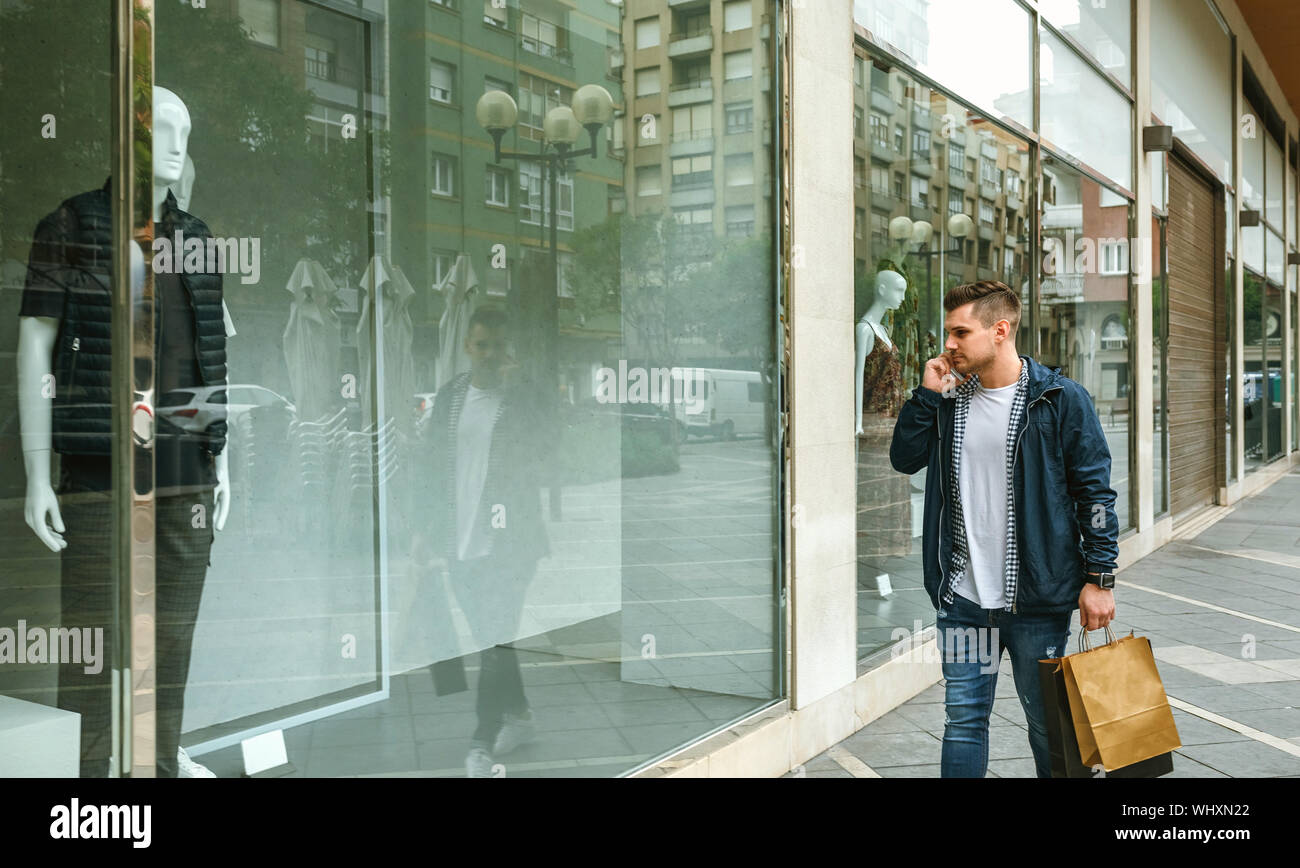 Man with shopping bags in front clothing store Stock Photo - Alamy
