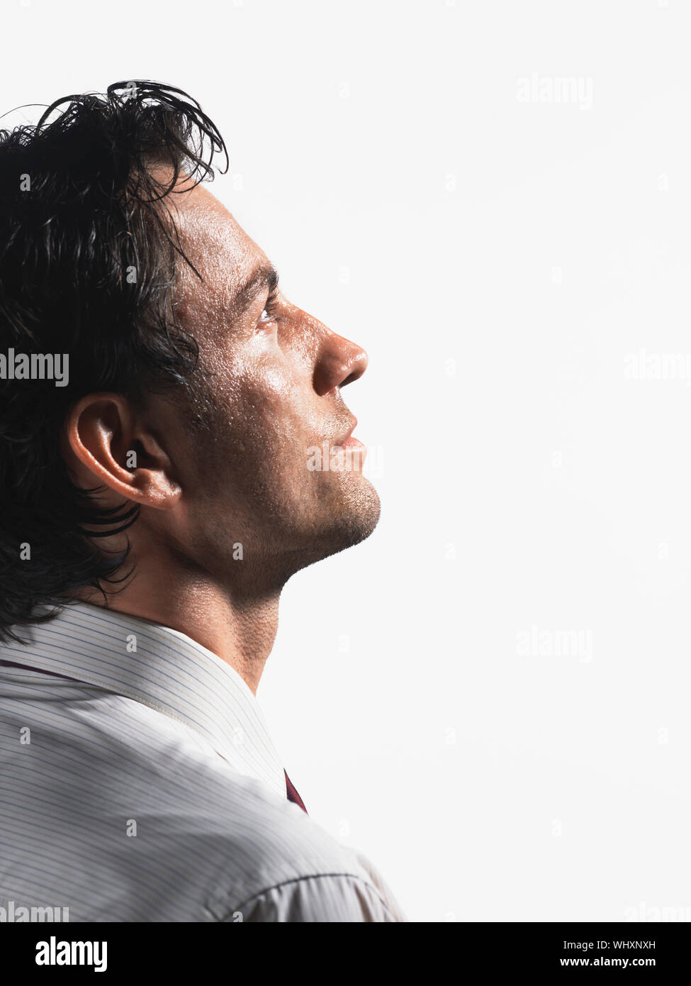 Closeup side view of a tired young businessman staring into space ...