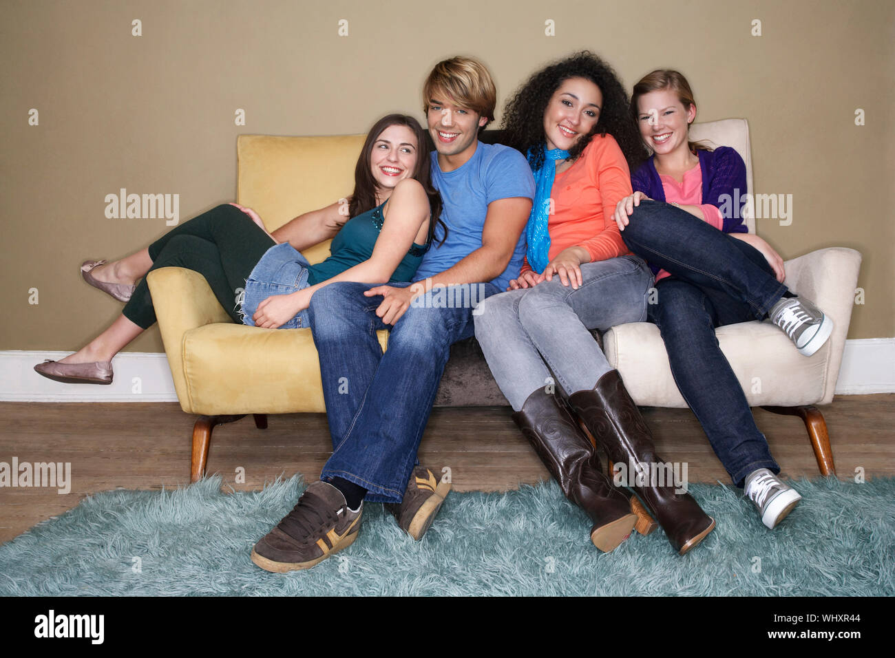 Full length portrait of four friends sitting on sofa Stock Photo - Alamy