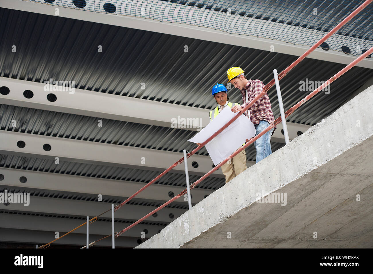 Low angle view of construction manager and worker examining building ...