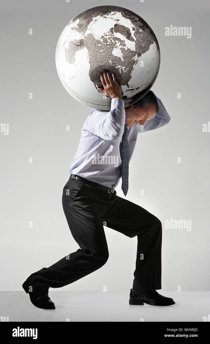 Full length side view of a businessman struggling to carry globe on ...