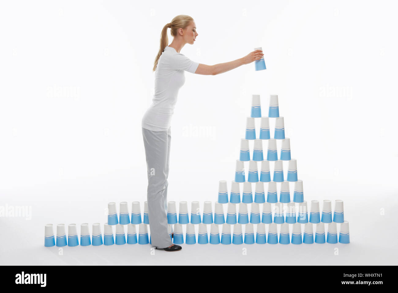 Full length side view of a woman stacking plastic cups into pyramid ...