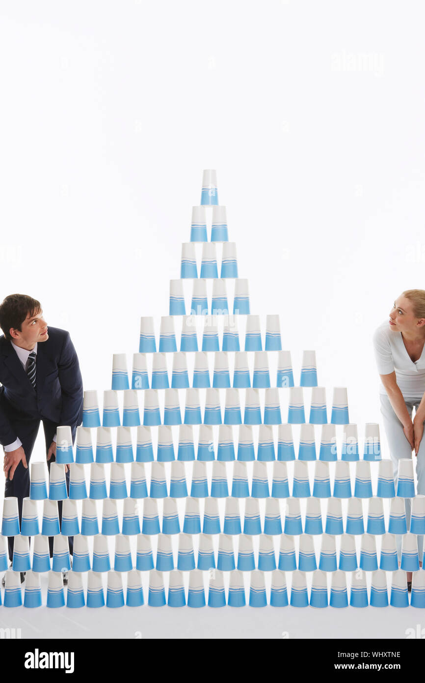 Man and woman admiring pyramid of stacked plastic cups against white ...