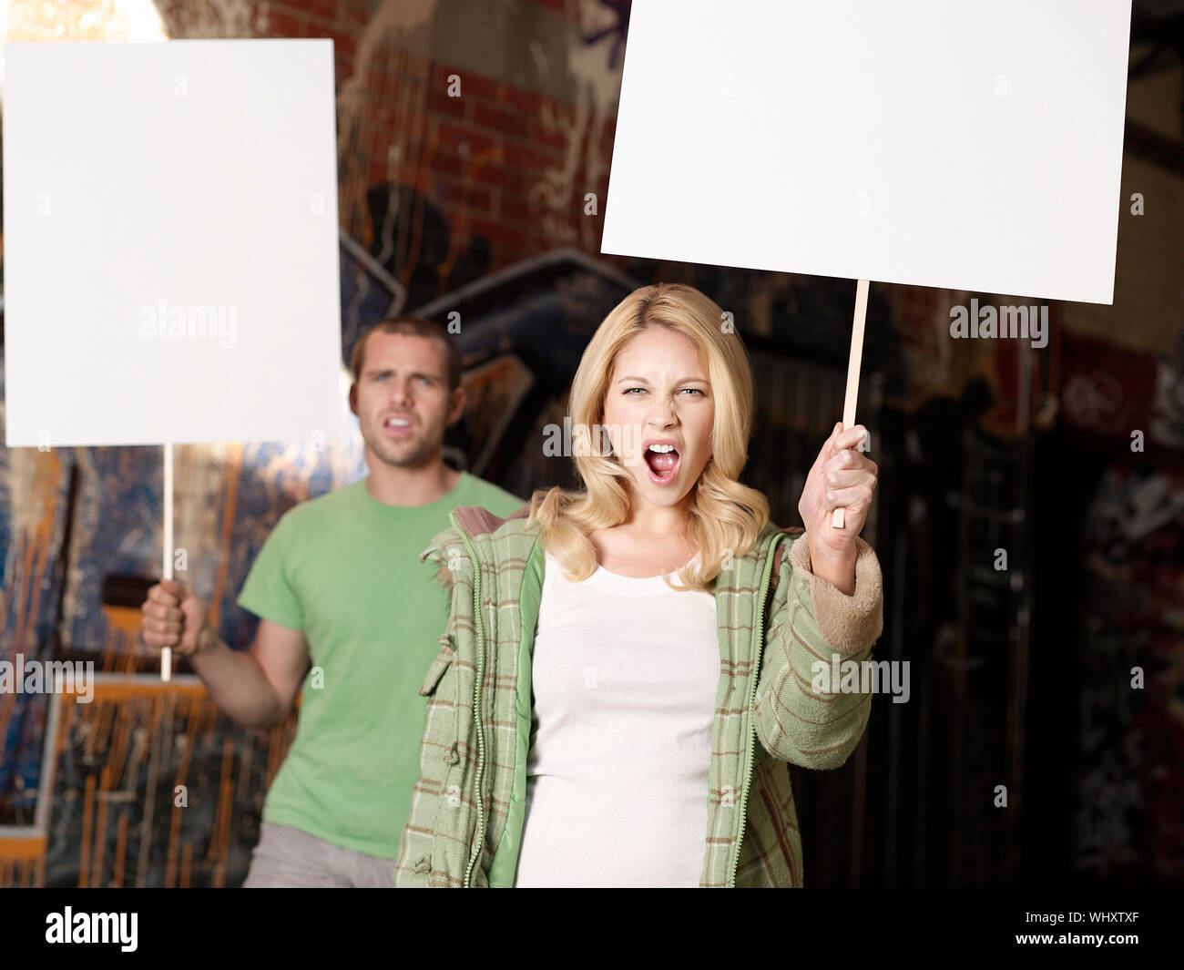Portrait of a young woman and man holding blank demonstration placards ...