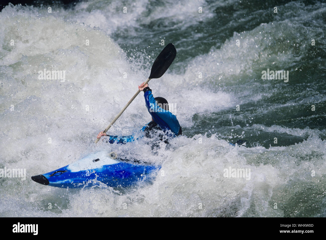 Side view of a male kayaker paddling through white water rapids Stock ...