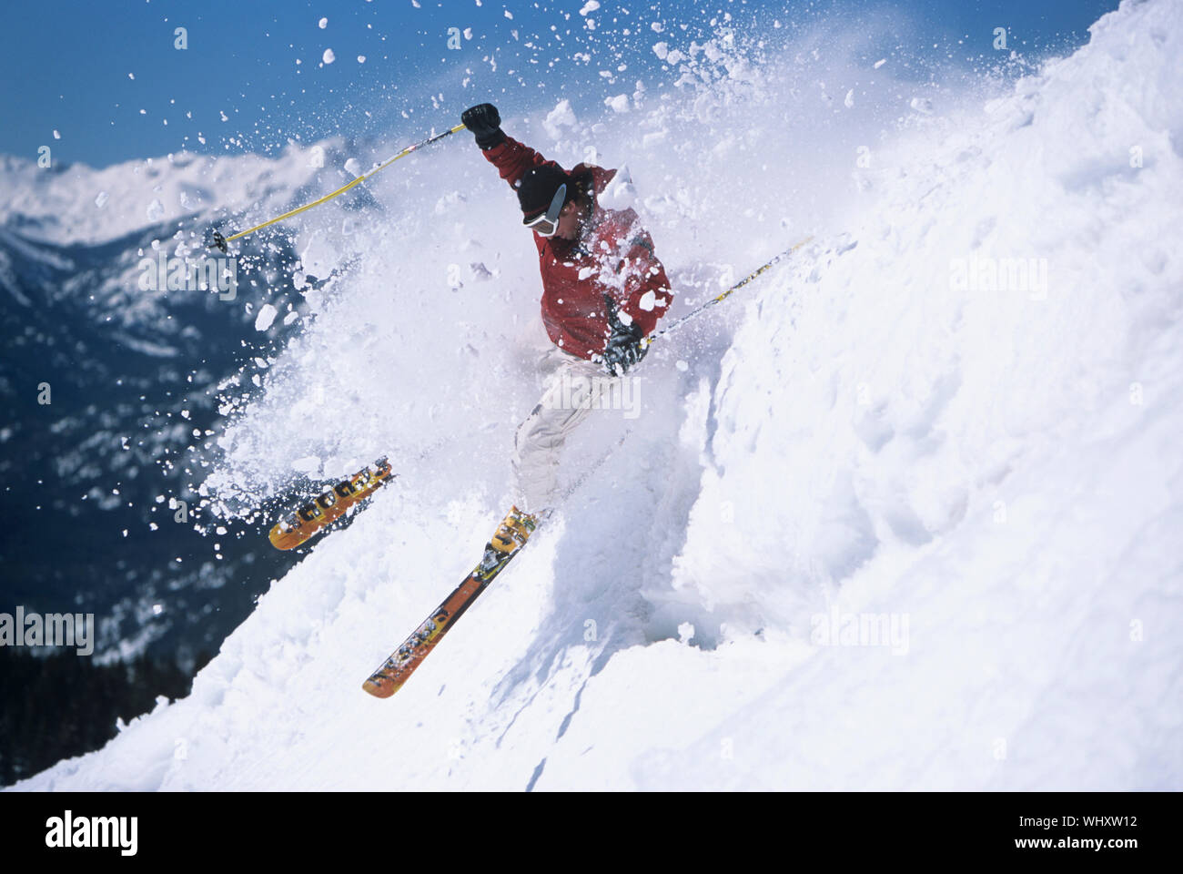 Side view of a male skier skiing through powdery snow on ski slope ...