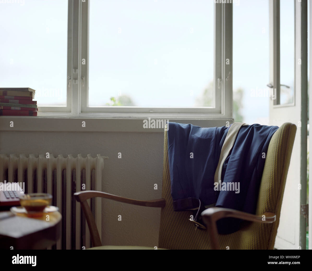 Closeup of clothes on back of armchair by window and open door Stock ...