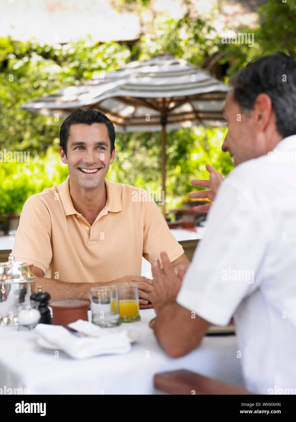 Two happy men conversing at an outdoor café Stock Photo - Alamy