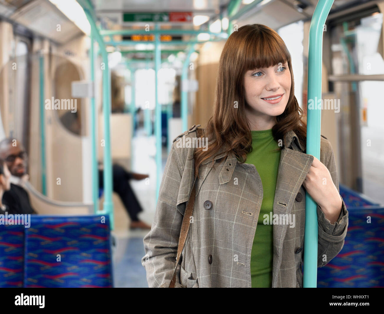 Smiling young woman standing in commuter train holding bar Stock Photo ...