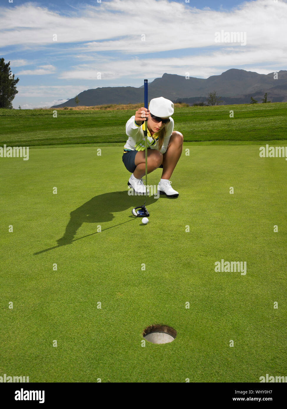 Full length of female golfer lining up a putt in golf course Stock ...