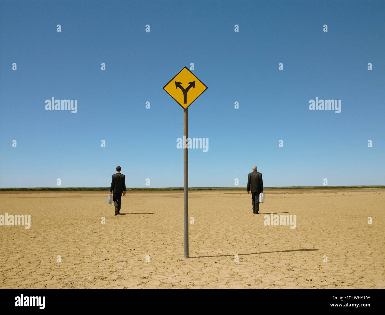 Rear view of businessmen with briefcases walking past road sign in ...