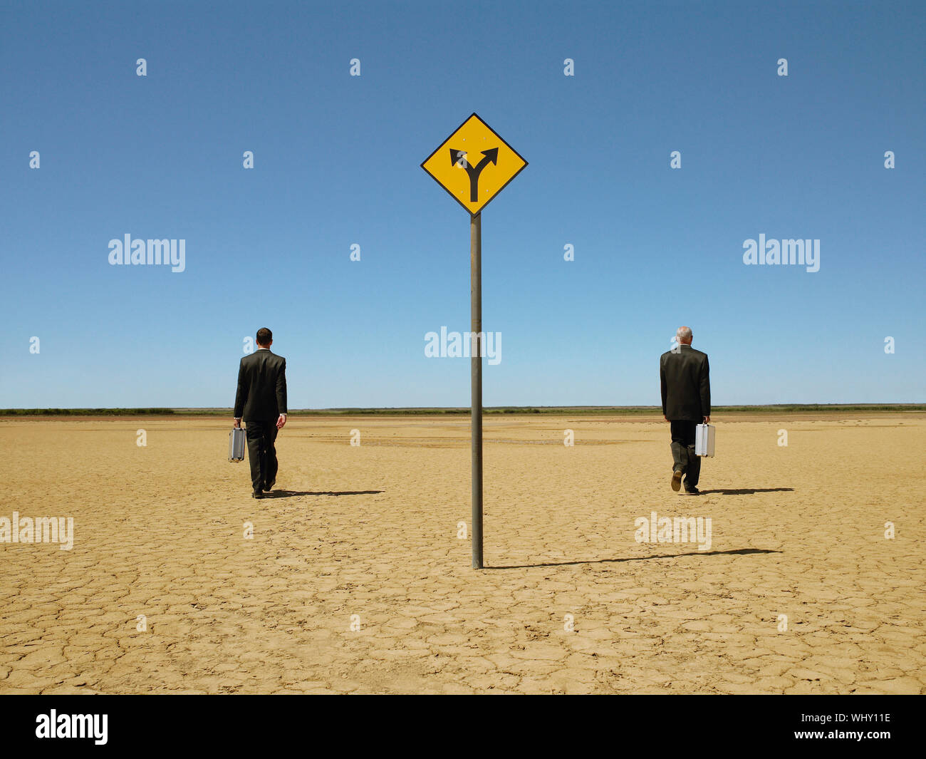 Rear view of businessmen with briefcases walking past road sign in ...