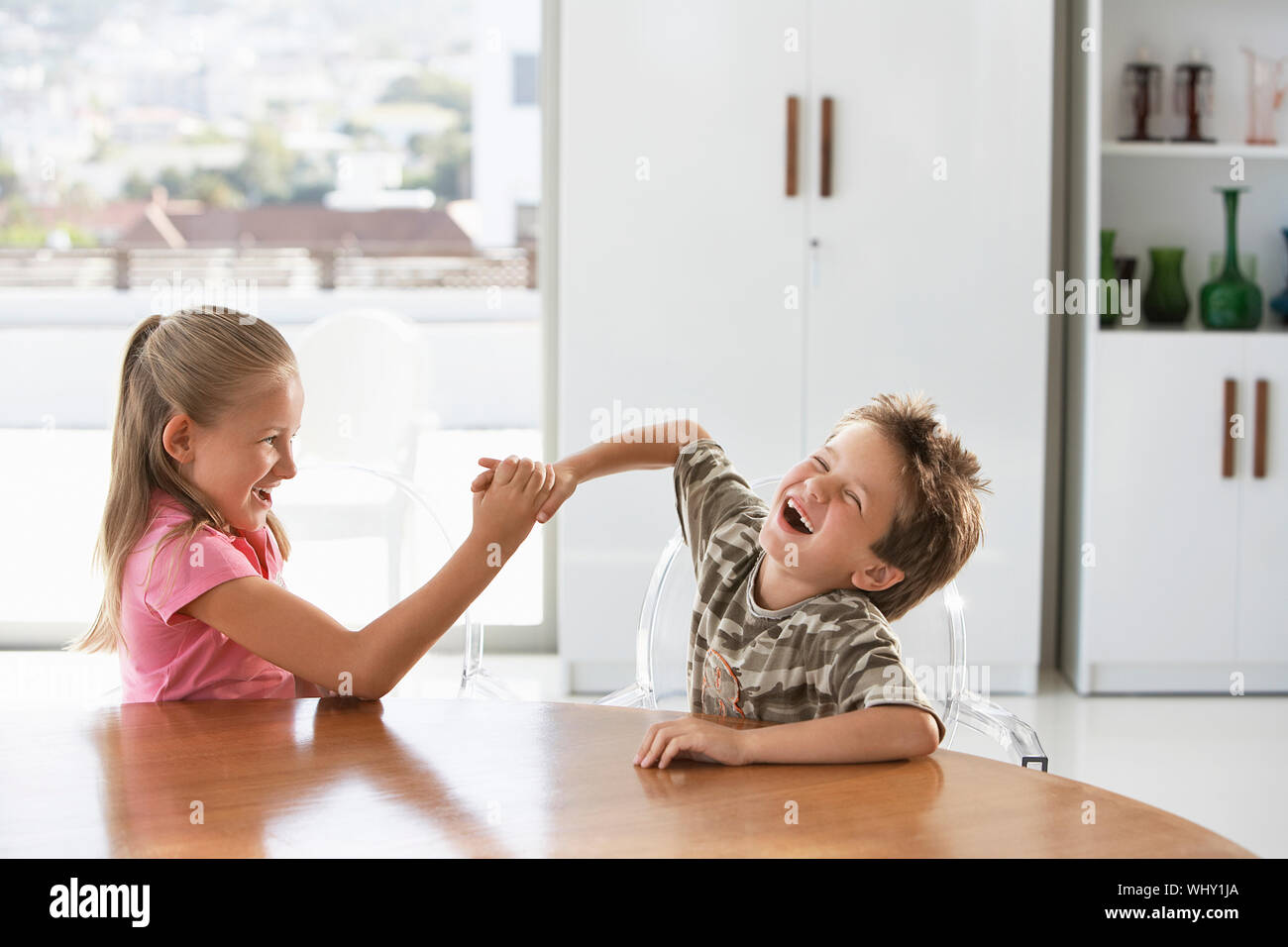 Playful young girl and boy fighting at dining table Stock Photo - Alamy