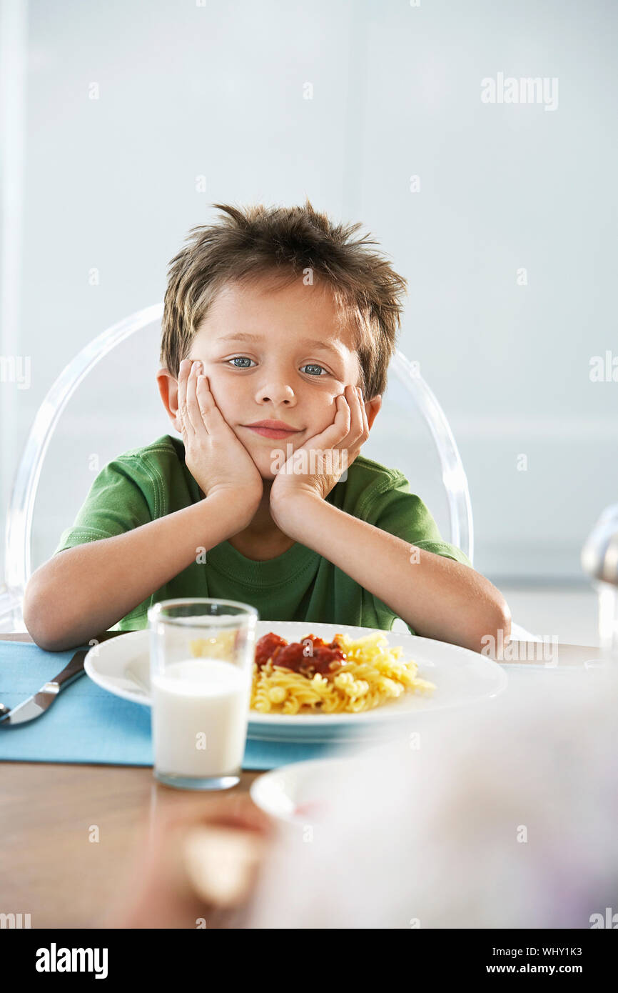Portrait of bored young boy sitting at breakfast table Stock Photo - Alamy