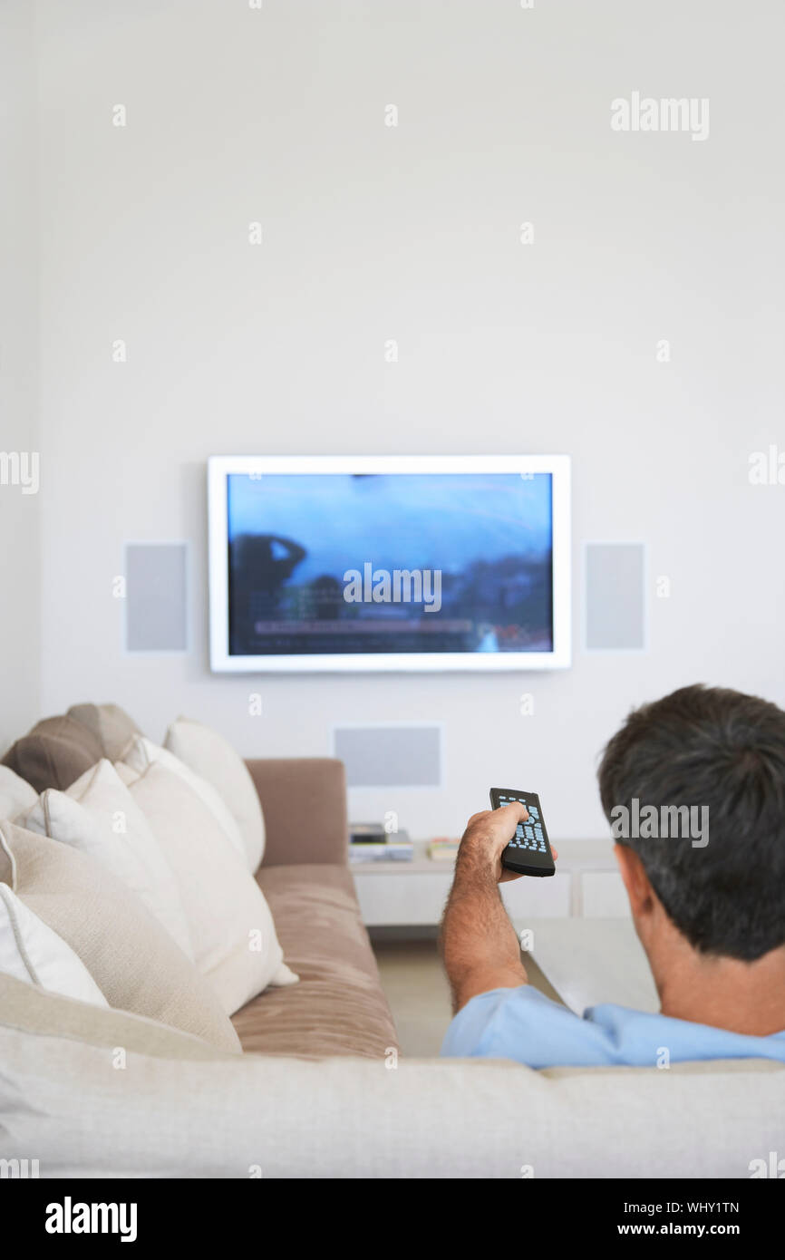 Rear view of middle aged man watching television in living room Stock ...