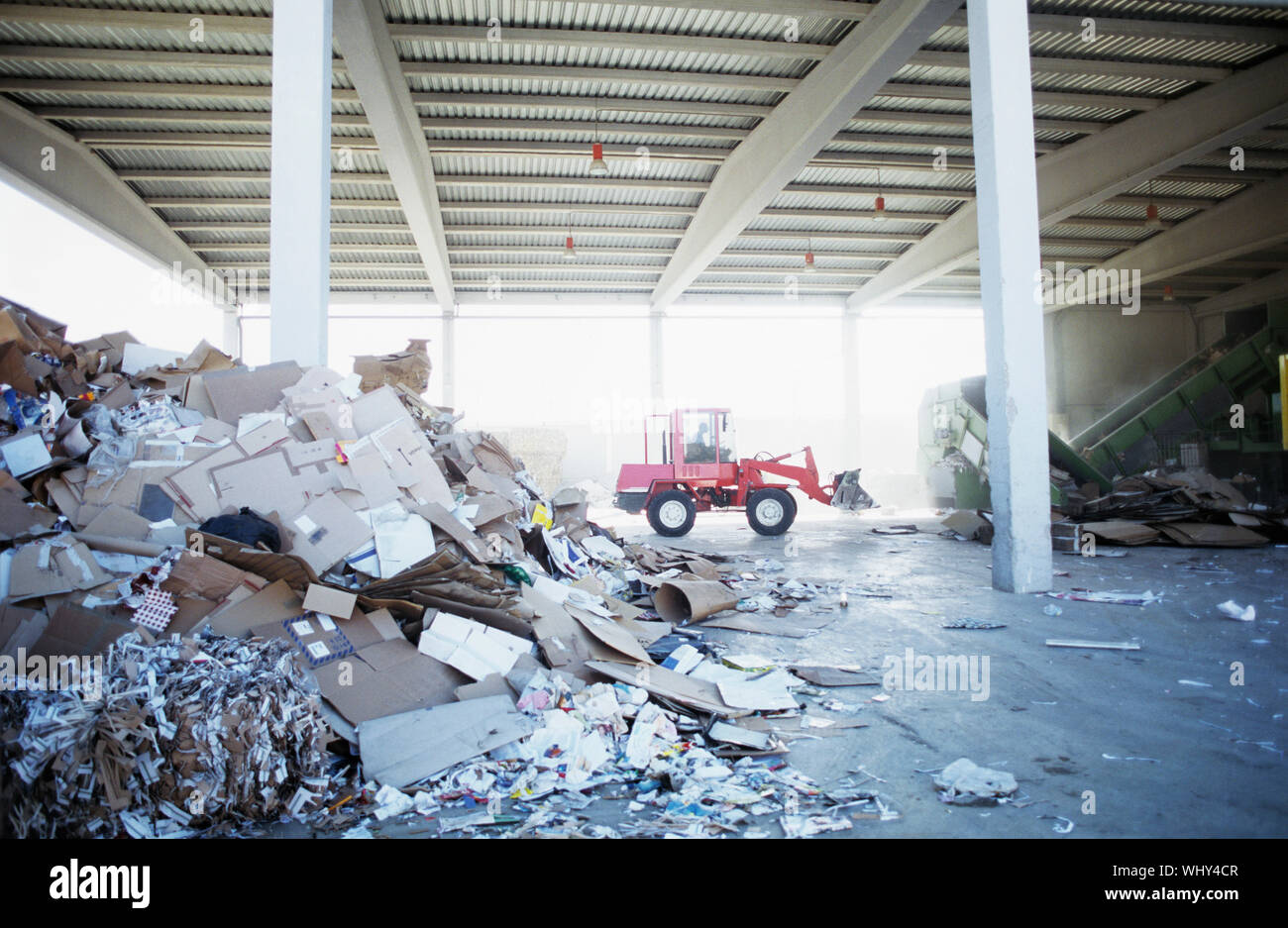 Heap of paper waste with digger truck in background at recycling plant ...