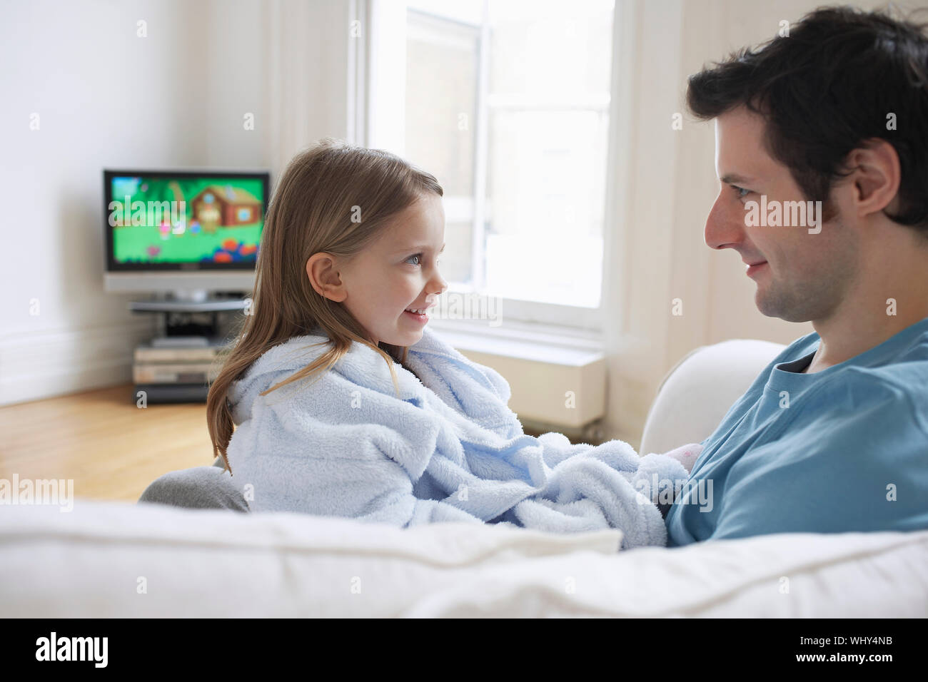 Side View Of A Father And Daughter Relaxing On Sofa In Living Room