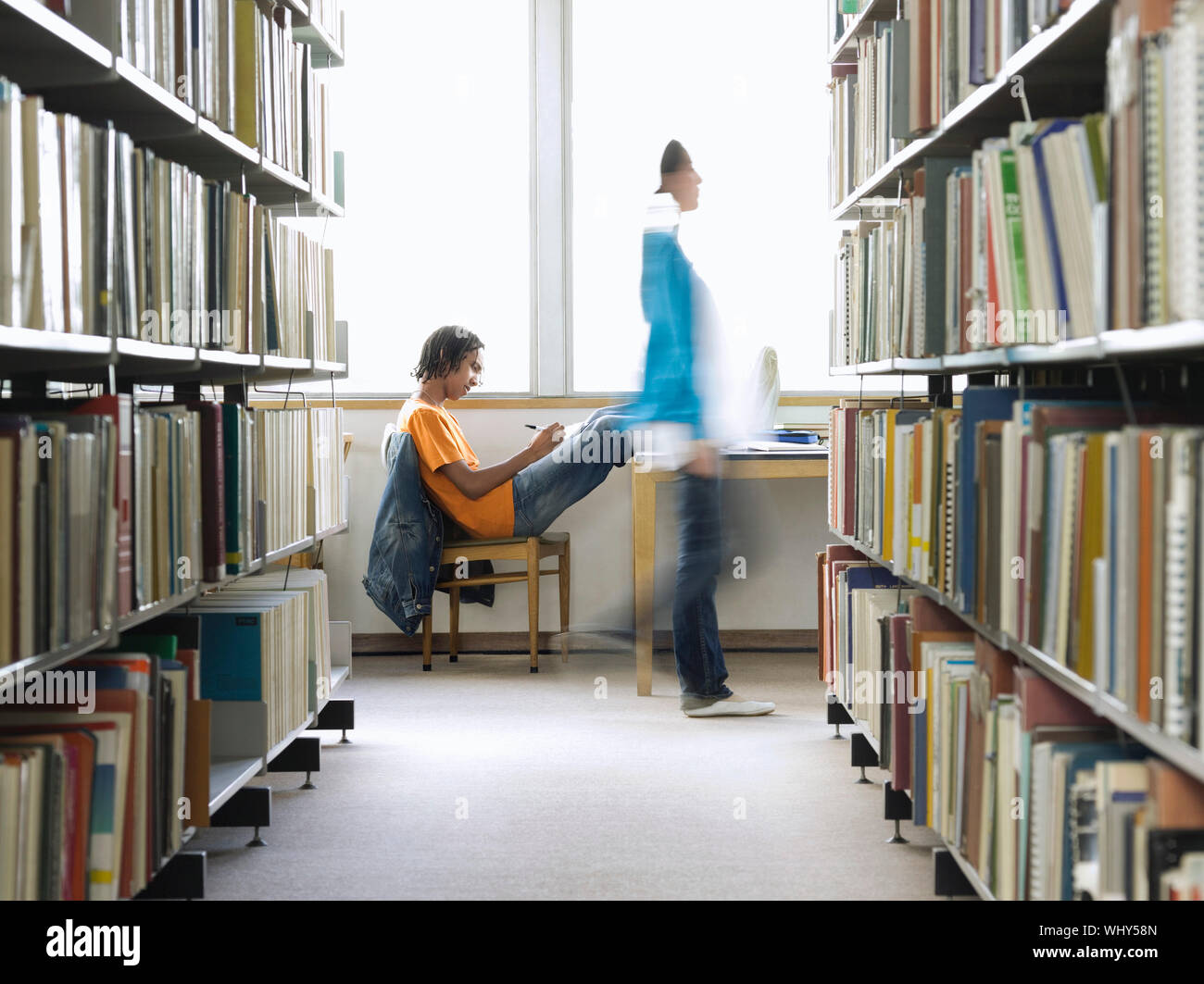 Side view of a young male college student doing homework in the library ...