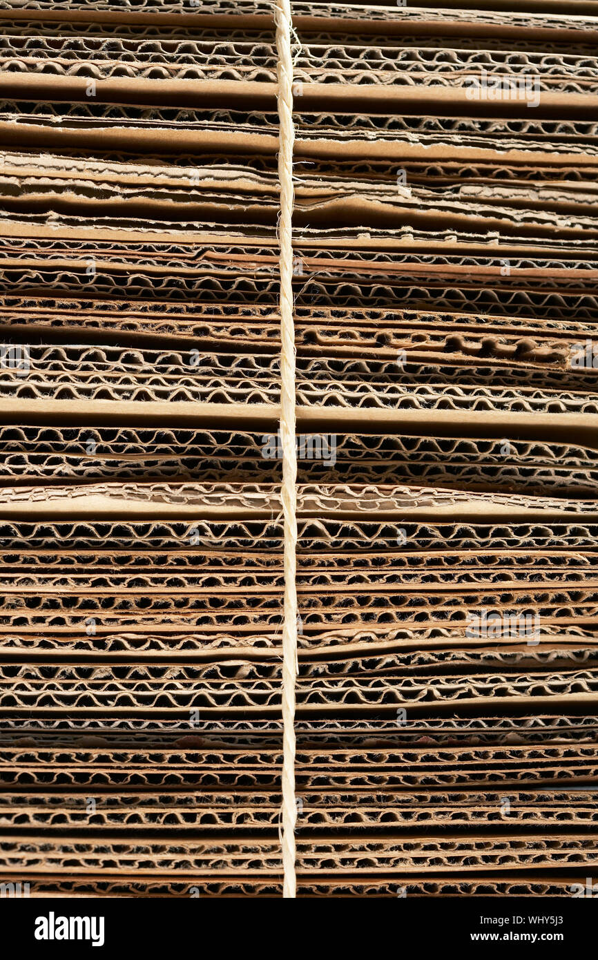 Bundle of corrugated cardboard tied with string close-up full frame ...