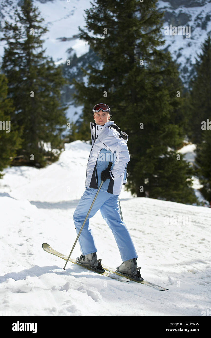 Full length side view of a female skier standing on ski slope Stock ...
