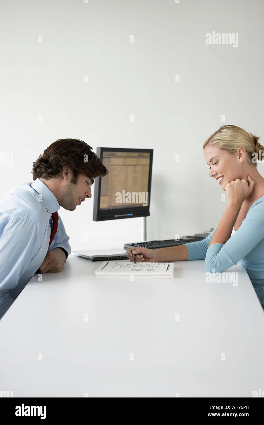 Side view of a businessman and woman sitting at office desk Stock Photo ...
