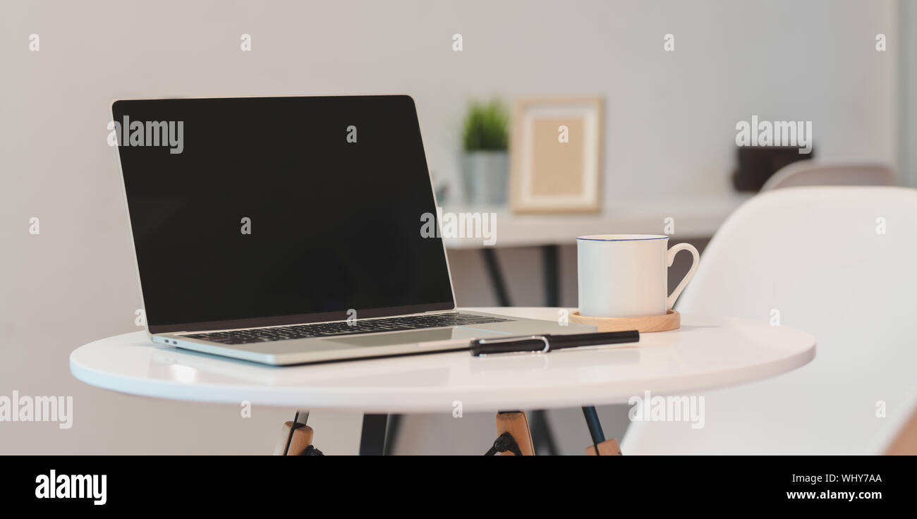 Open blank screen laptop computer in minimal workplace with coffee cup ...