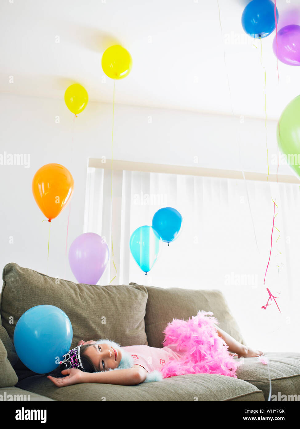 Young smiling girl lying on sofa and looking up at balloons Stock Photo ...