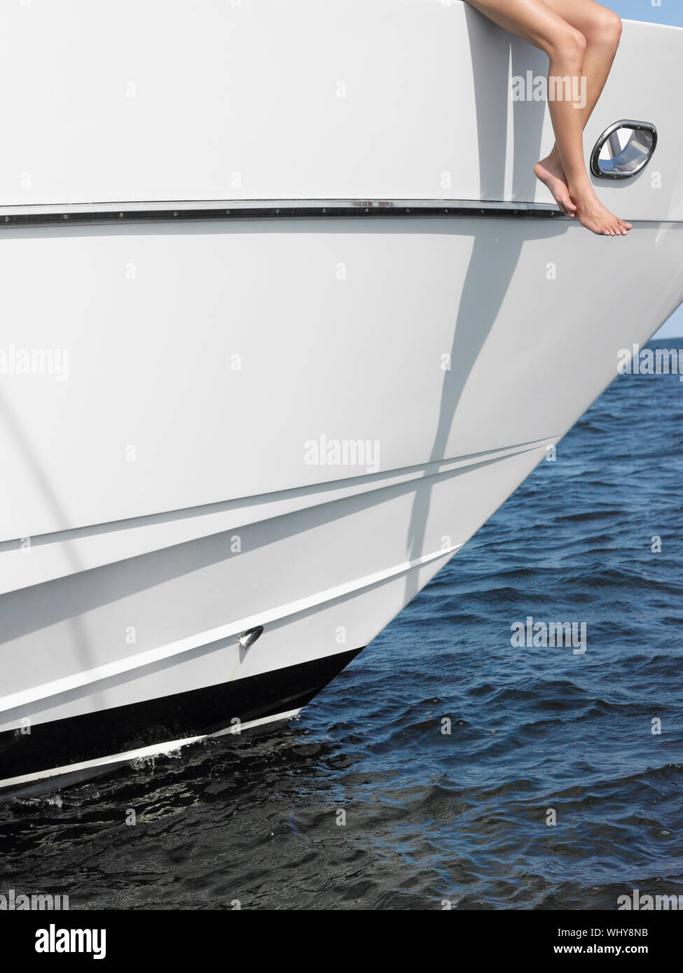 Young woman sitting at edge of yacht with legs dangling overboard Stock ...