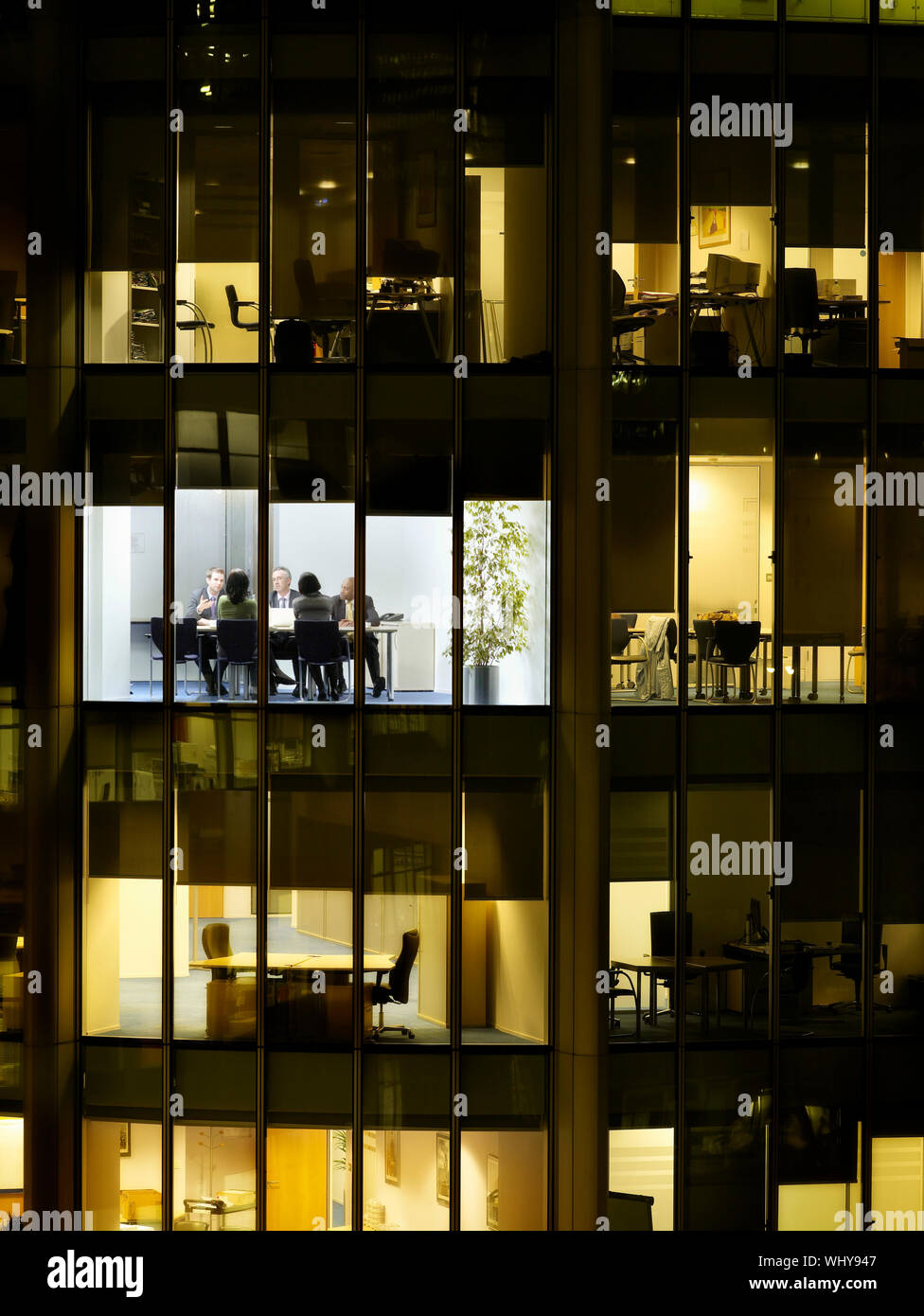 Business meeting viewed through illuminated window of office block at ...