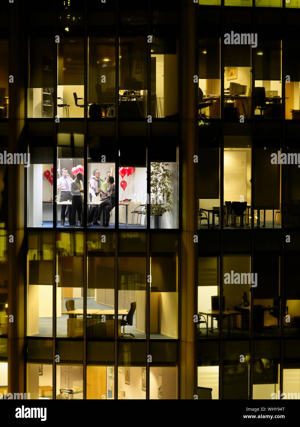 View of business people having office party through window at night ...