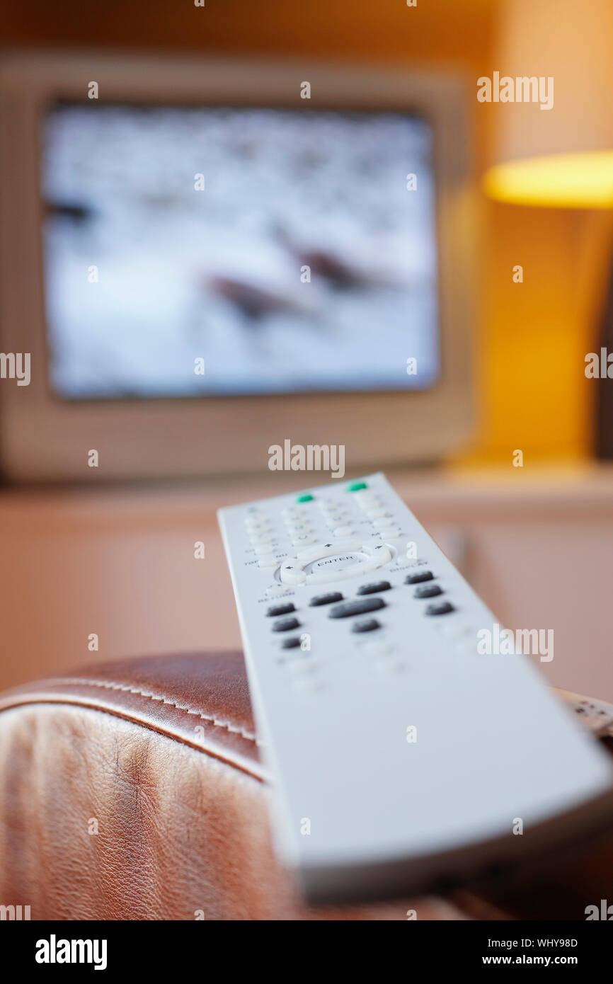 Remote control on leather armchair with television in background Stock ...
